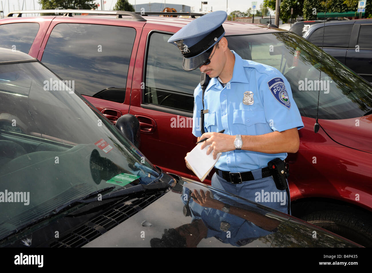 Police officer writes a ticket for parking violation Stock Photo - Alamy