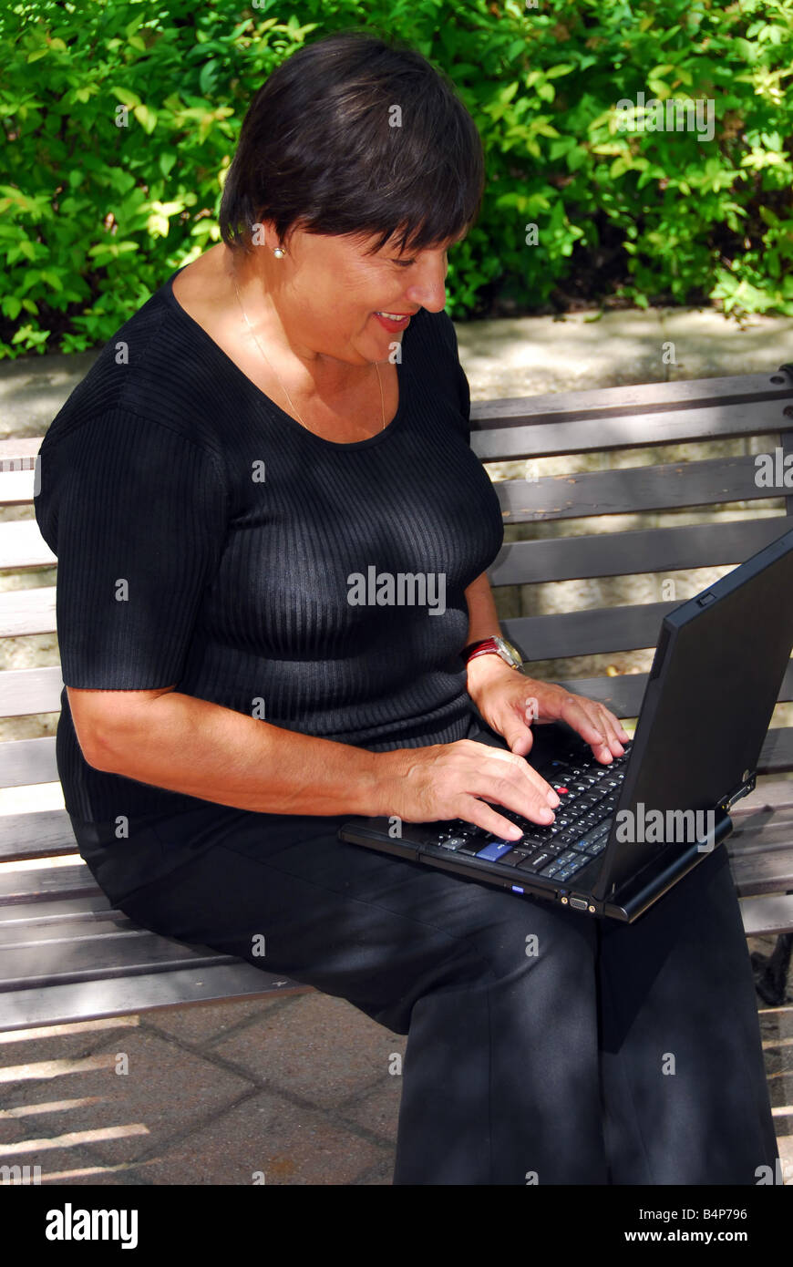 Mature woman typing on portable computer outdoor Stock Photo - Alamy
