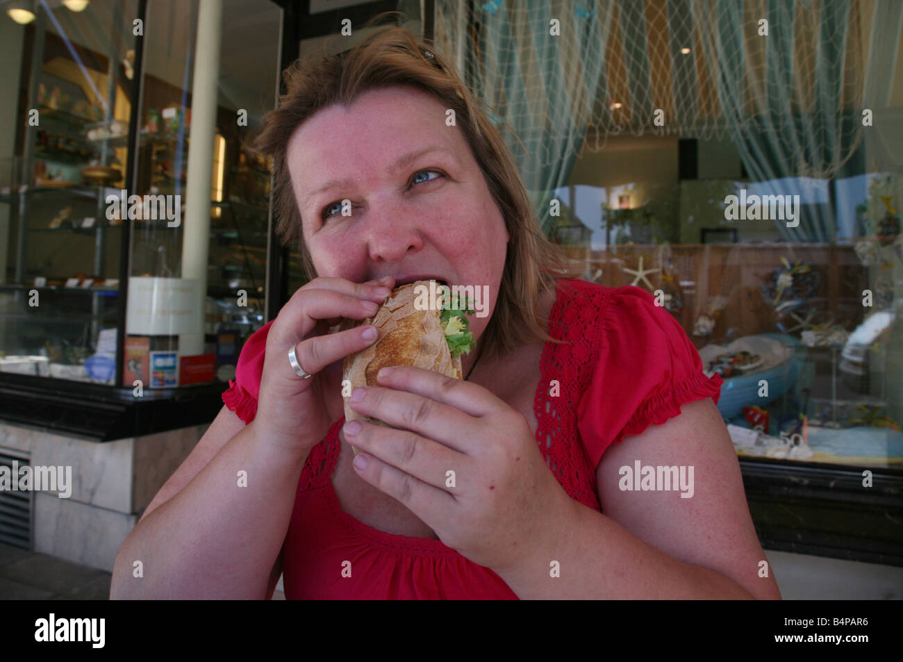 Overweight woman eating a large roll Stock Photo - Alamy