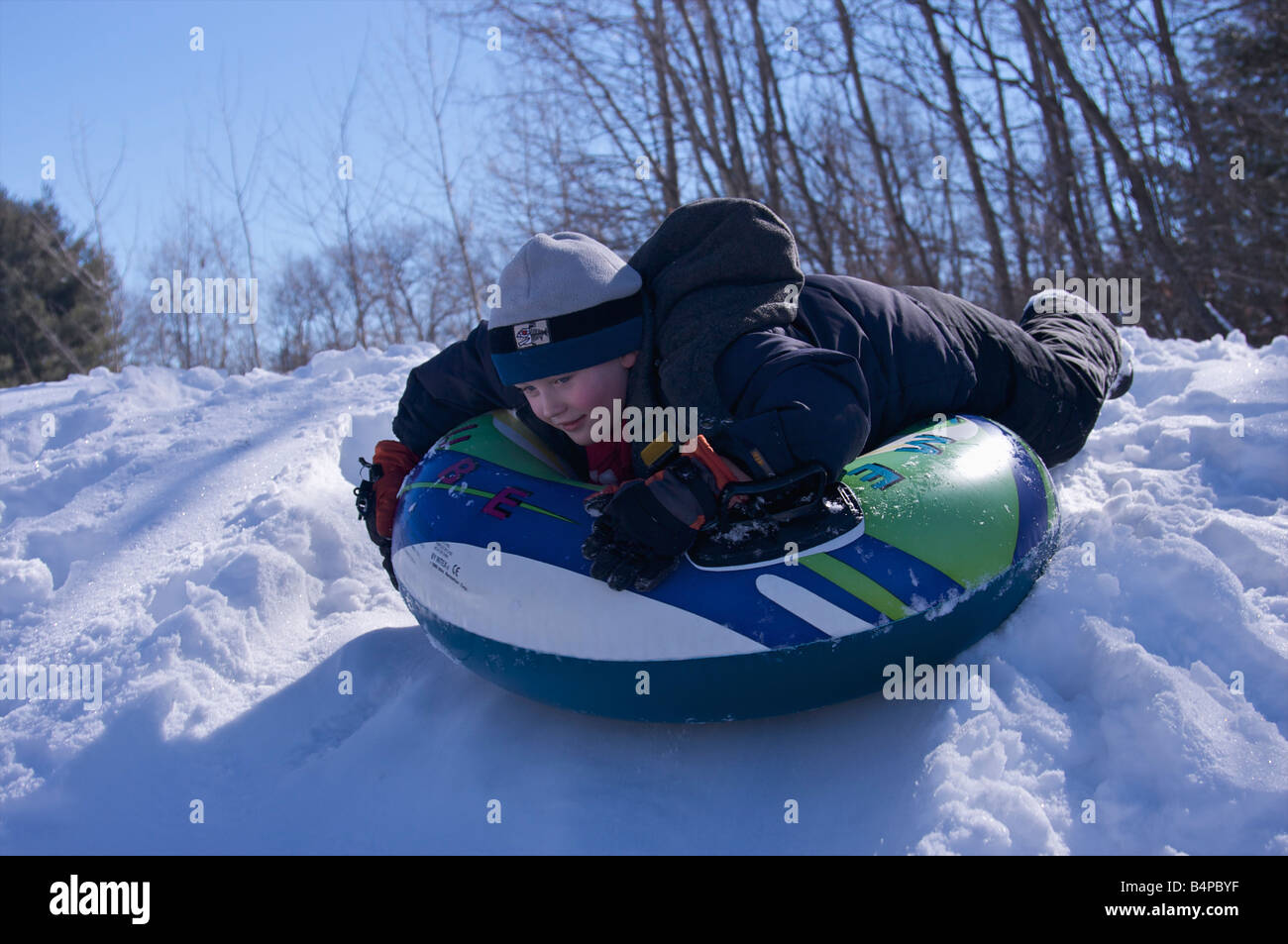 A boy tubes down a snow covered winter slope Stock Photo - Alamy