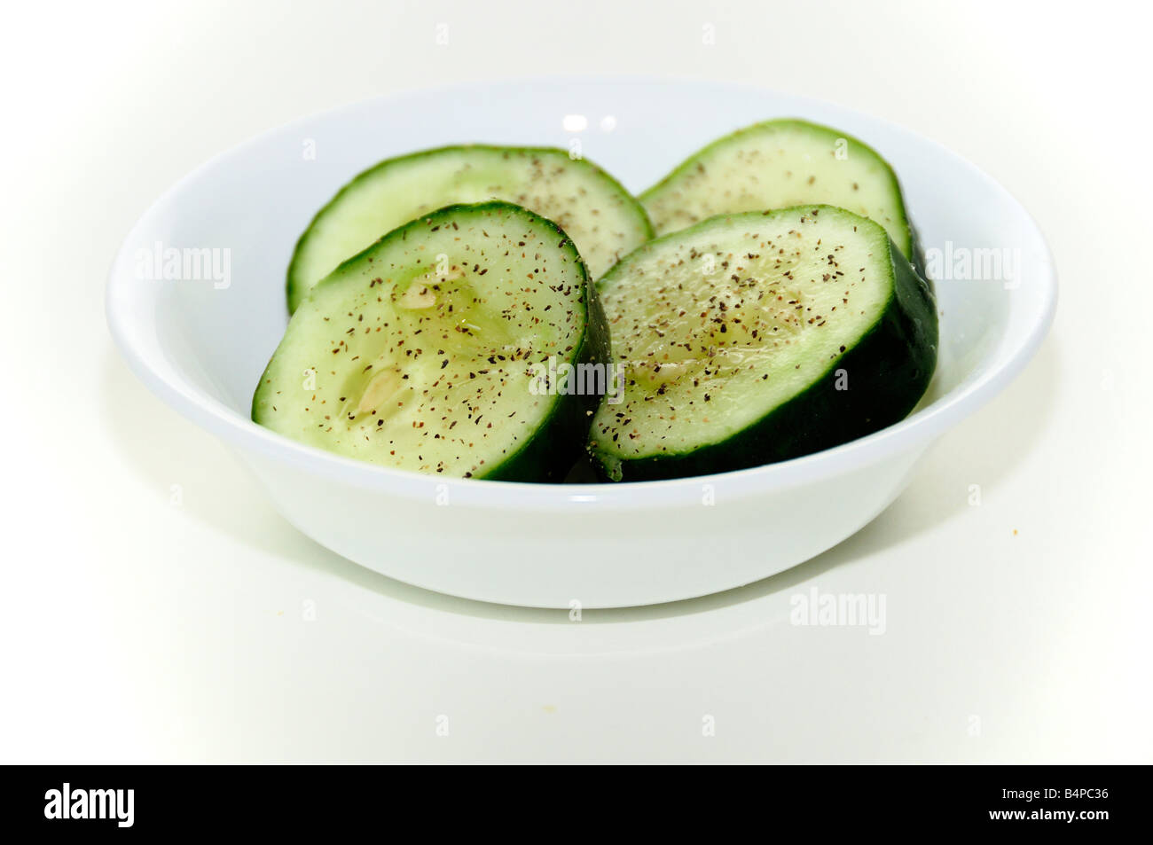 A small bowl containing sliced cucumbers on a white background Stock ...