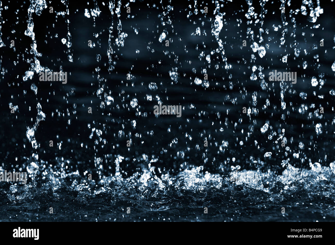 Falling water drops on dark background close up Stock Photo - Alamy