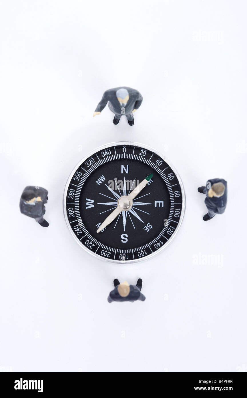 Male figurines around compass Stock Photo - Alamy