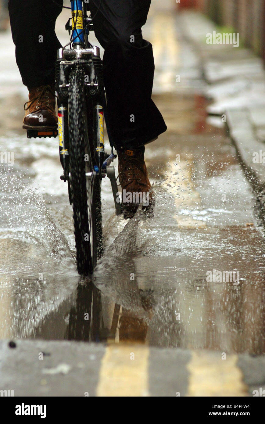 Man riding a bike through a puddle of rain on the road May 2005 Stock ...