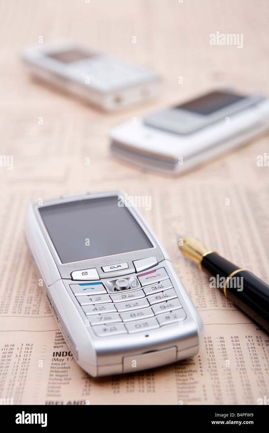 Mobile phones and pen on a financial newspaper Stock Photo - Alamy