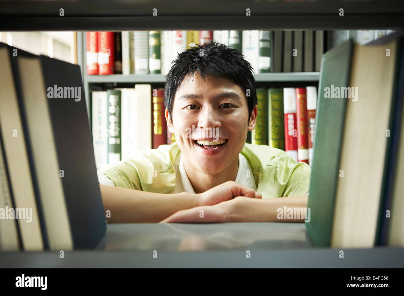 Young man smiling between shelves in library, portrait Stock Photo - Alamy