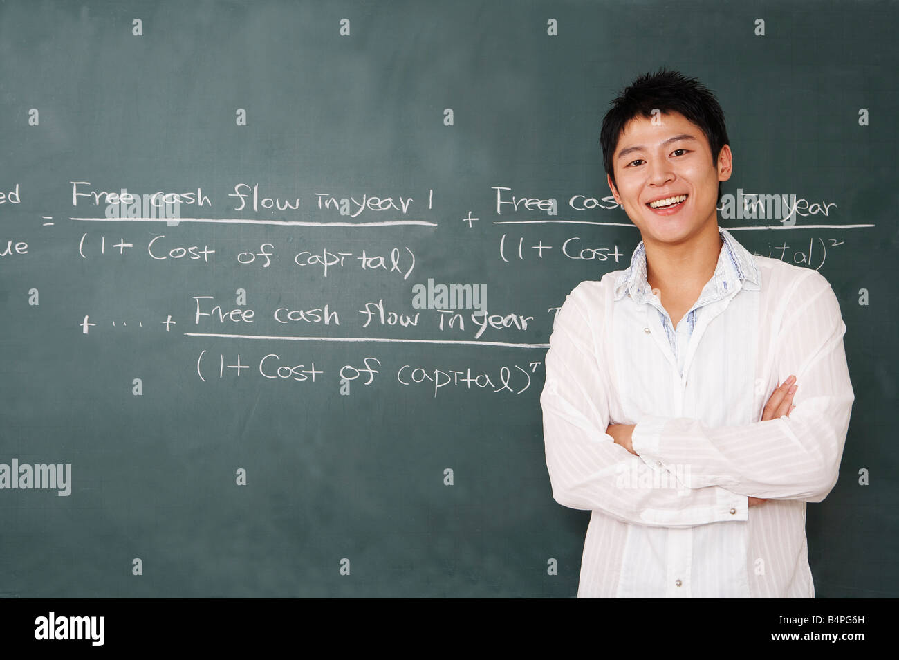 Young man standing by blackboard, portrait Stock Photo - Alamy