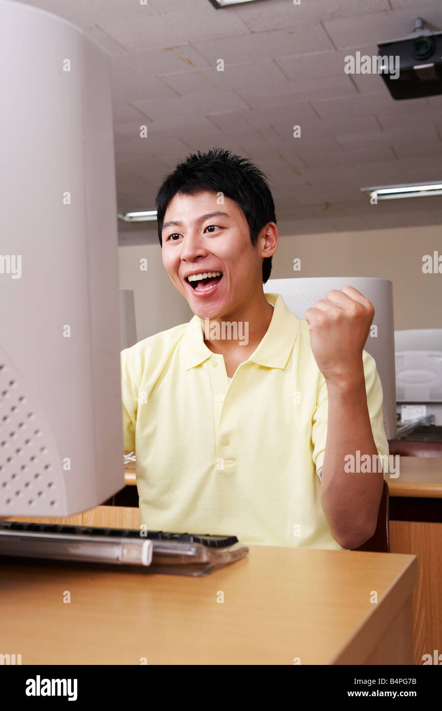 Young man using computer, cheering Stock Photo - Alamy