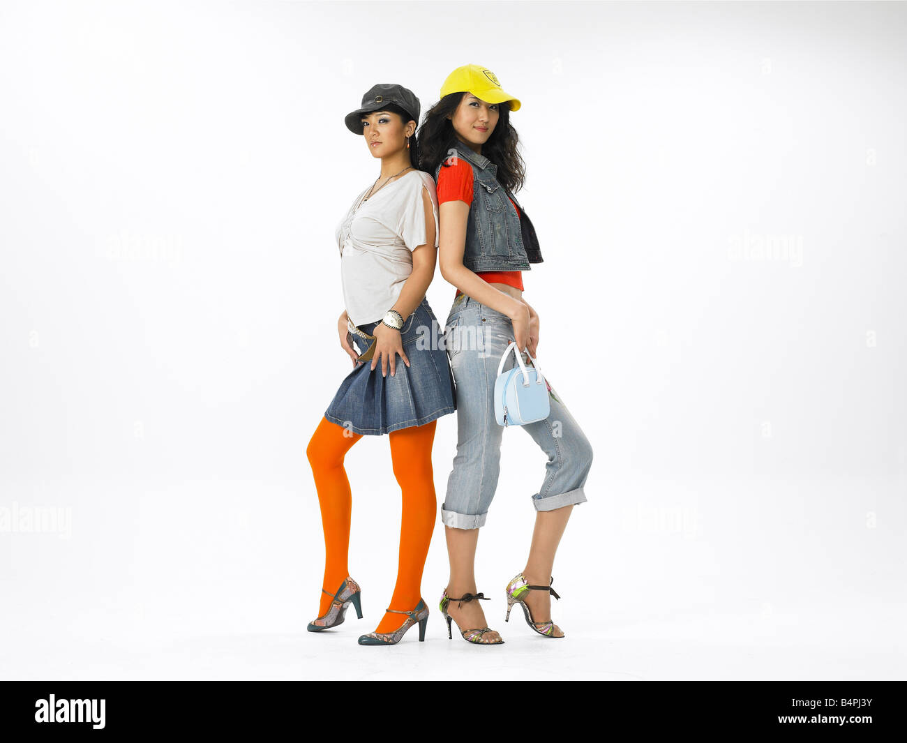 Portrait of young women standing back to back Stock Photo - Alamy