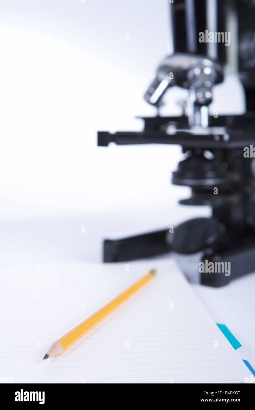 Pencil on book with microscope in the background Stock Photo - Alamy