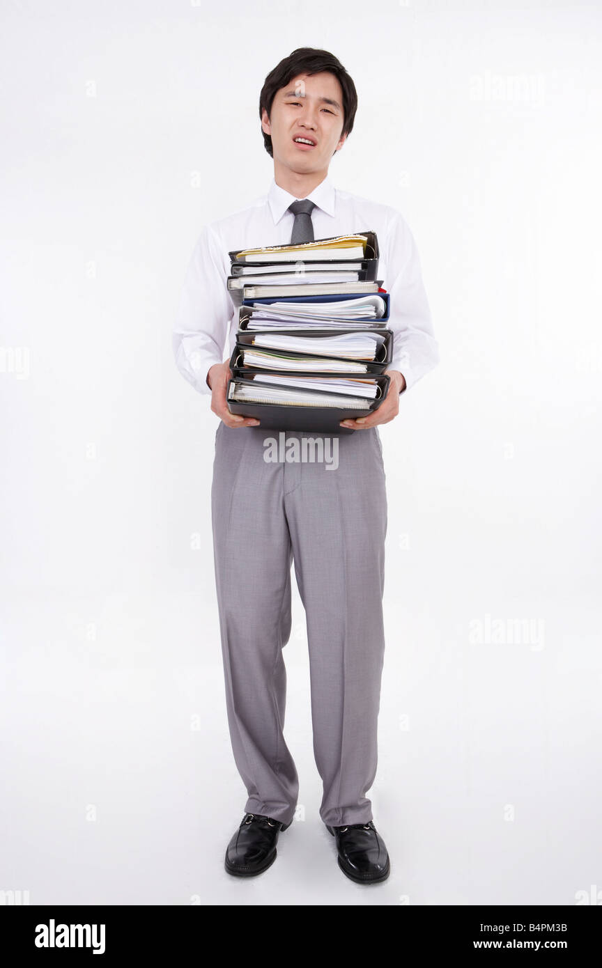 Young man carrying stacks of files, portrait Stock Photo - Alamy
