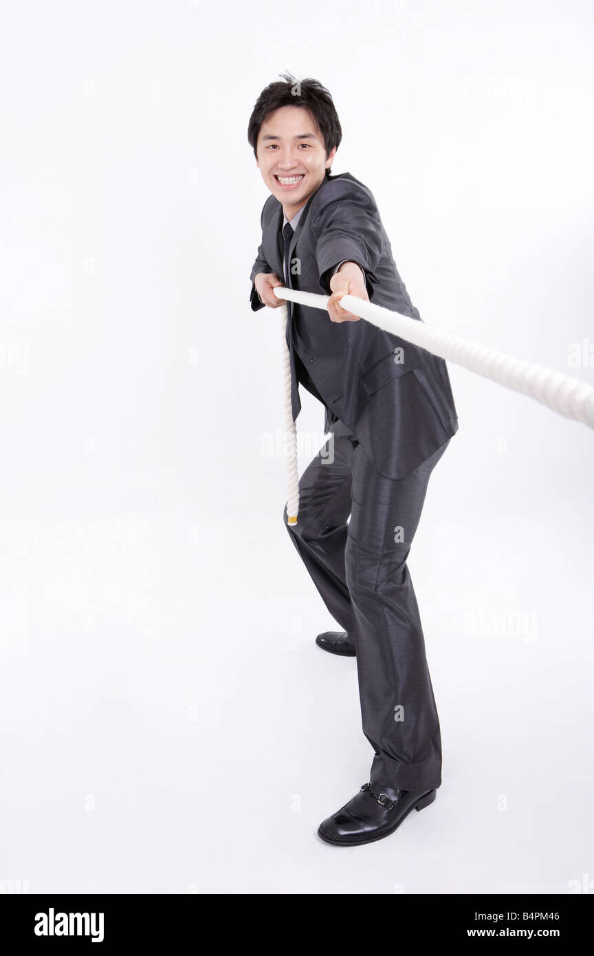 Cheerful businessman pulling rope Stock Photo - Alamy