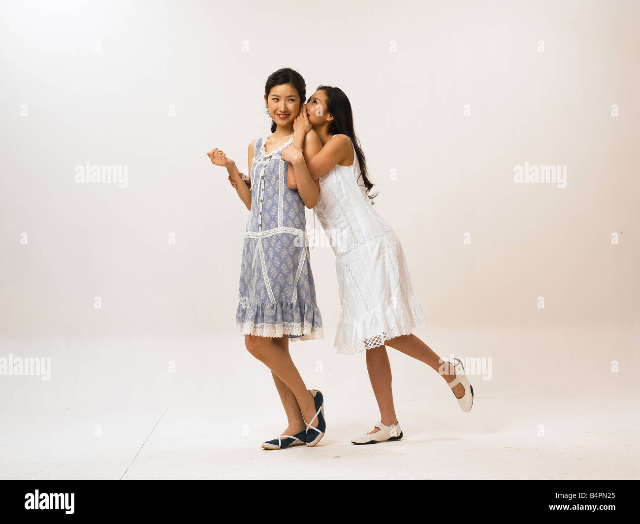 Two young women whispering Stock Photo - Alamy