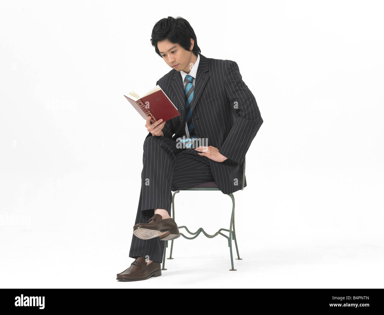 Young businessman sitting on chair and reading book Stock Photo - Alamy