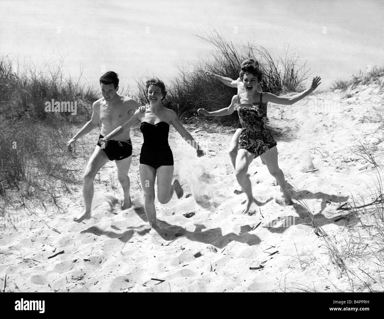 Seaside running in the sand Friends chasing each other at the beach in ...