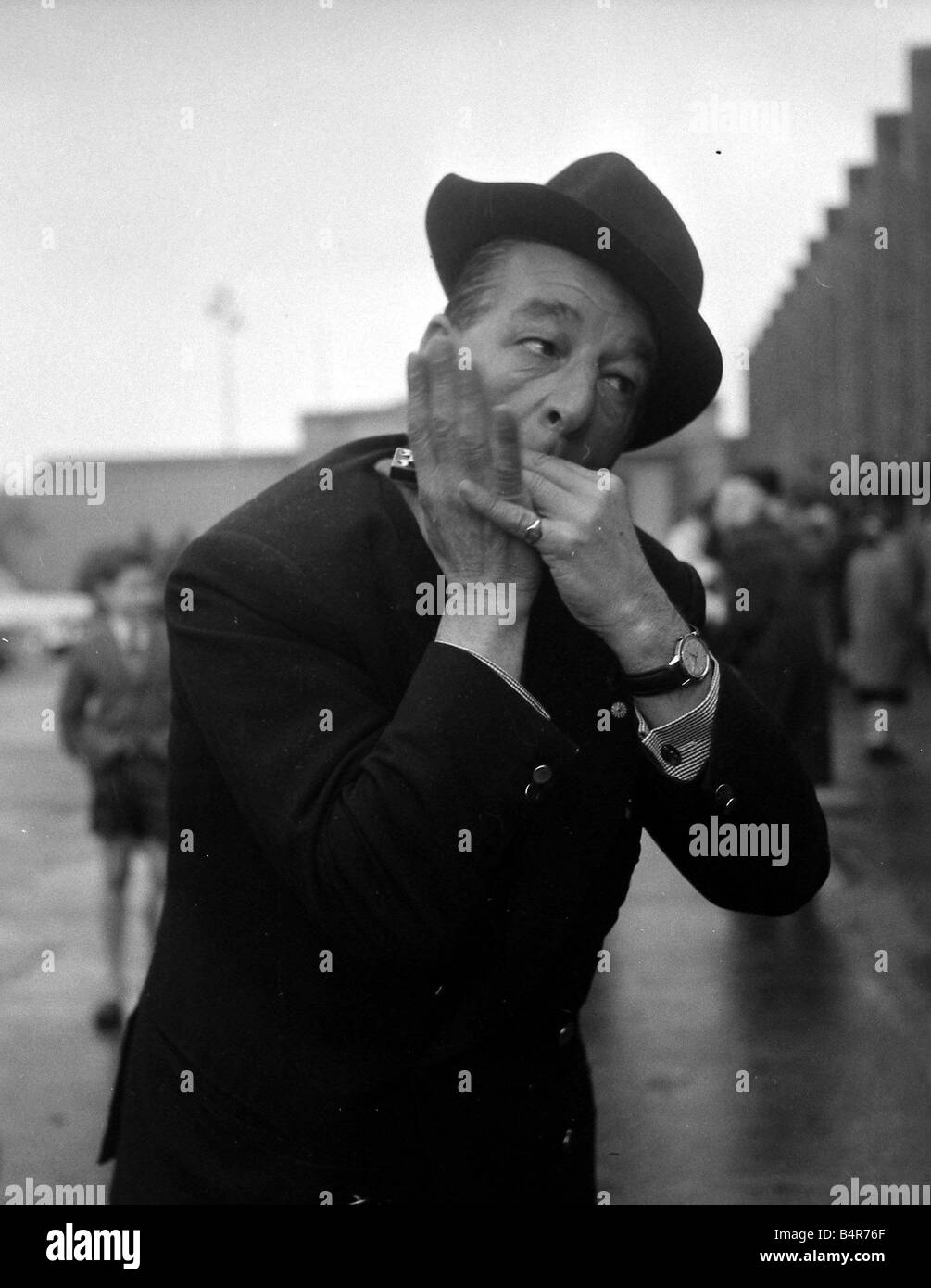 Entertainer Jimmy Edwards wearing a top hat entertaining crowds outside ...