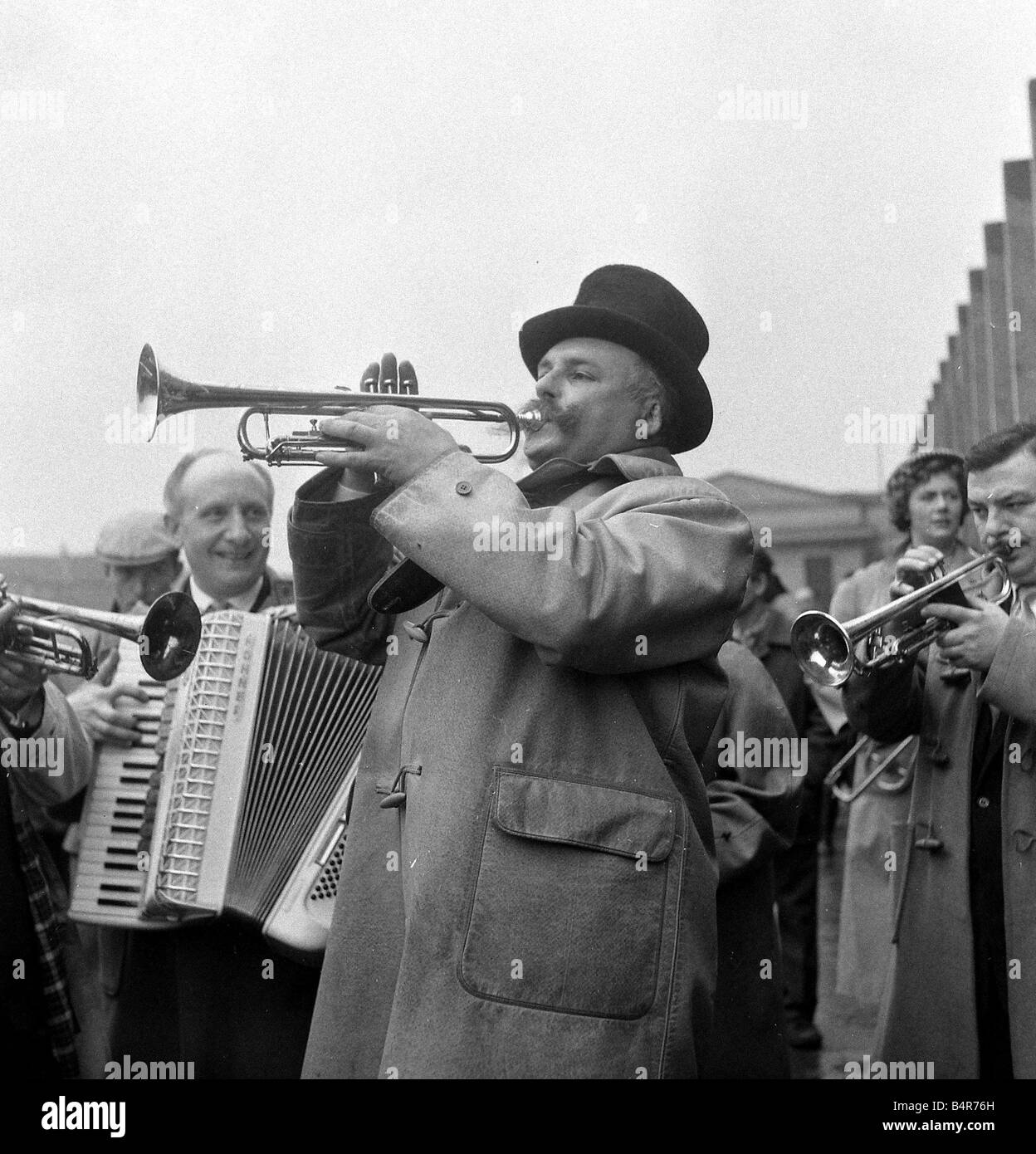 Entertainer Jimmy Edwards wearing a top hat and his group of buskers ...