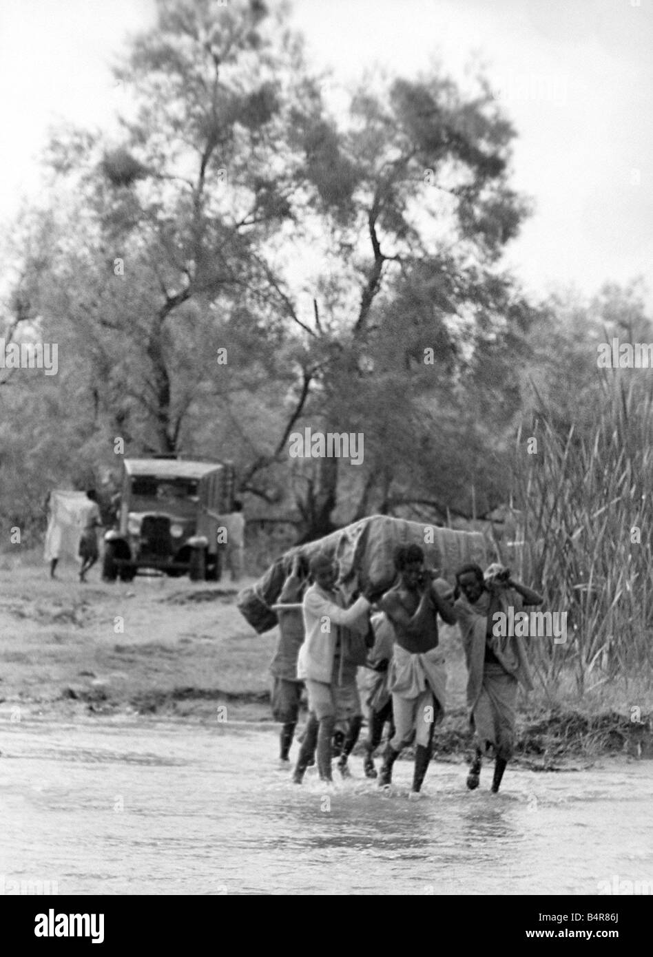Local men of Abyssinia carring heavy objects across a river Circa 1935 ...
