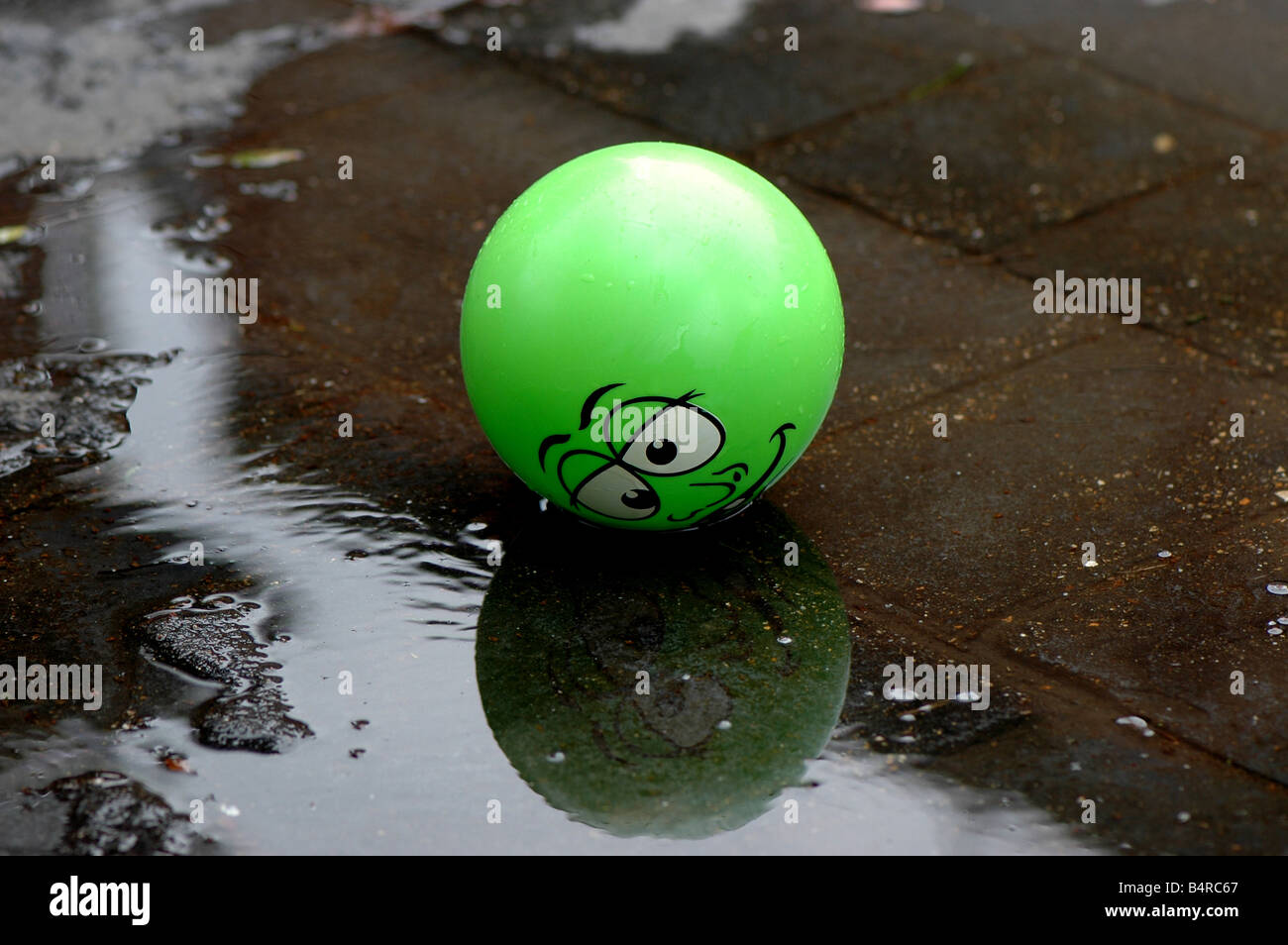 A ball looking at its reflection in a puddle Stock Photo - Alamy