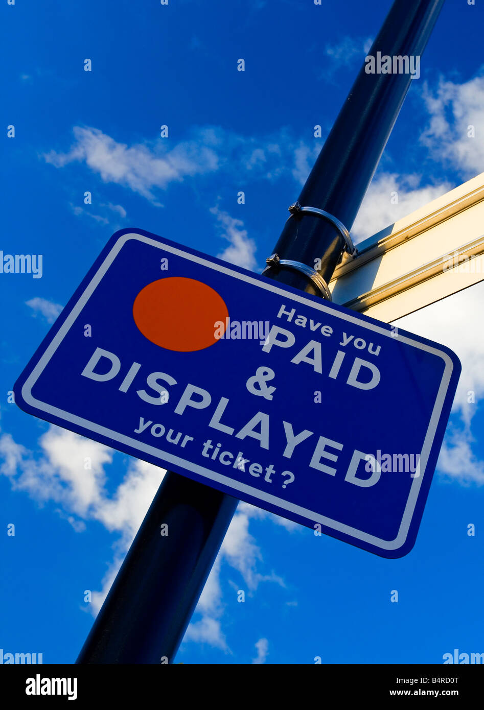 Pay and Display sign attached to a post in a car park with blue sky ...