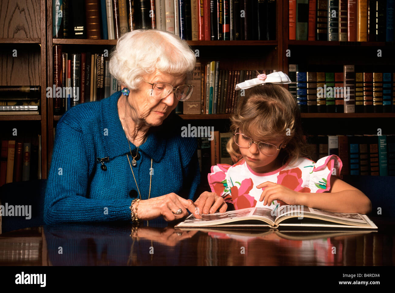 Grandmother reading to granddaughter in library Stock Photo - Alamy