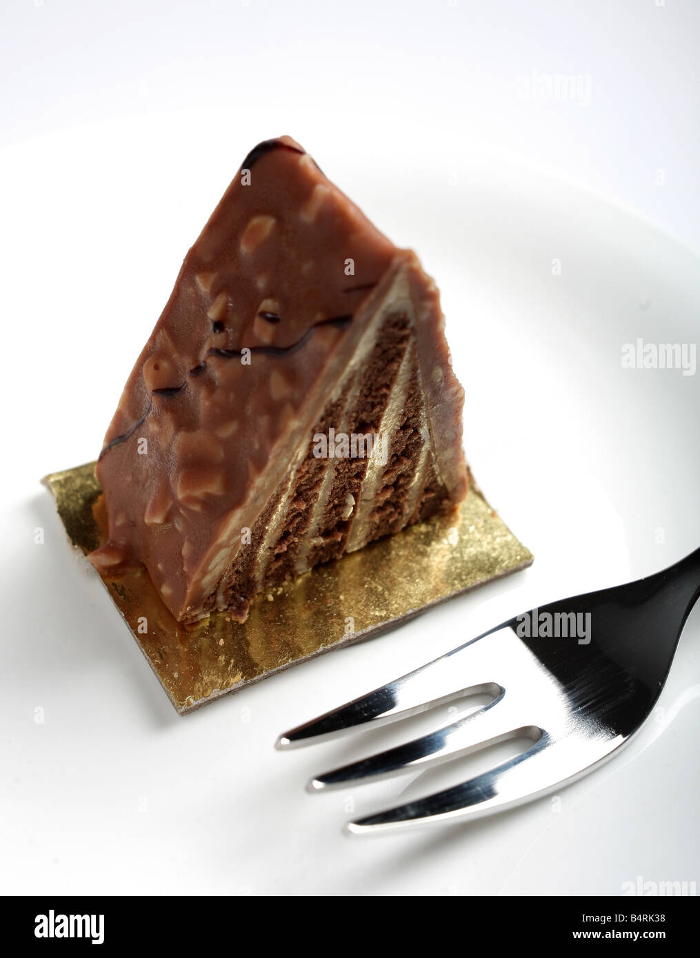 A miniature chocolate mousse triangle on a plate with a fork Stock ...