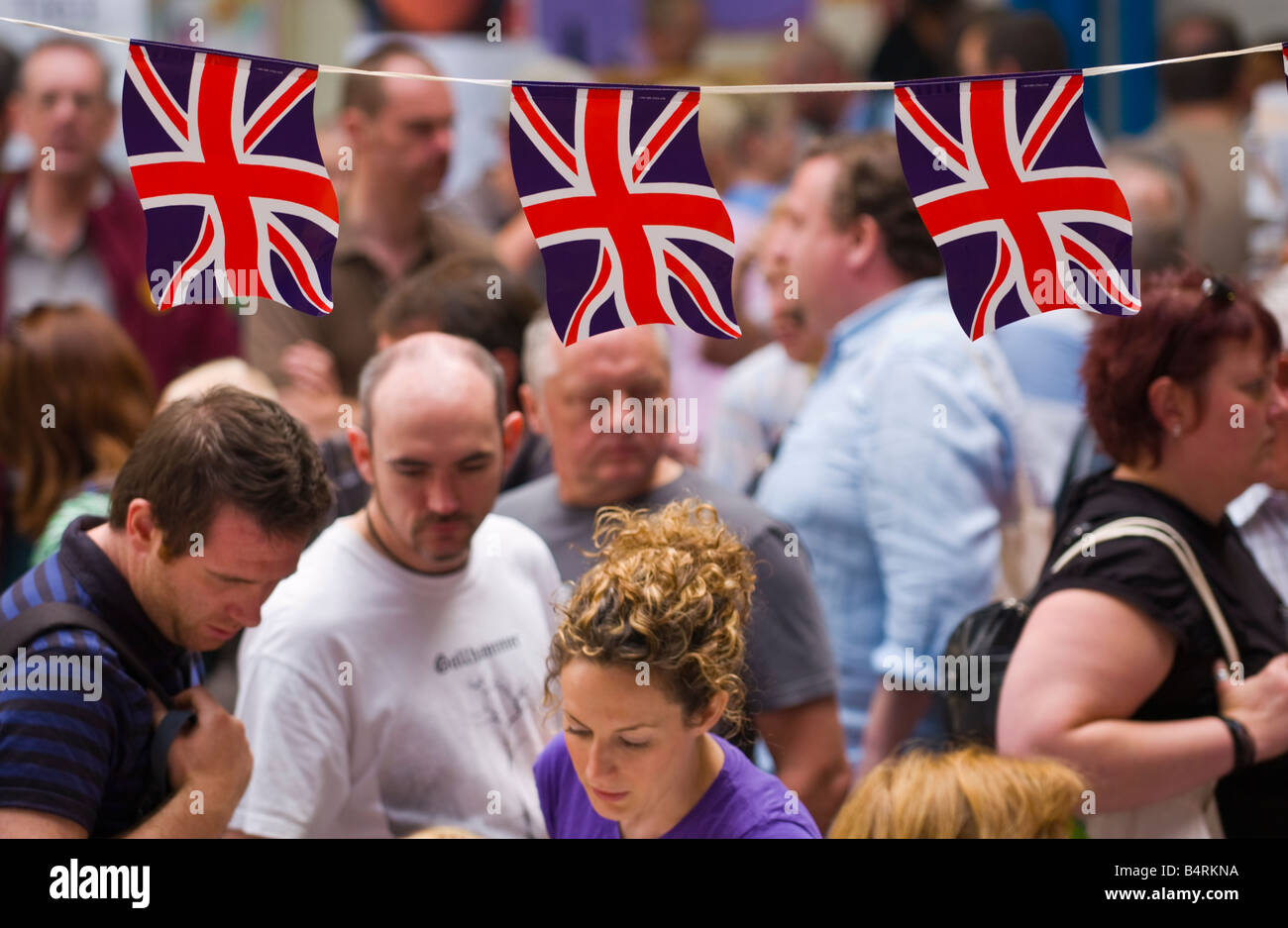 Union Jack flags with crowd of people browsing stalls at Abergavenny ...