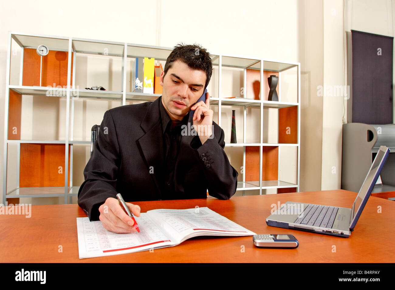 businessman using a telephone and writing at his desk Stock Photo - Alamy