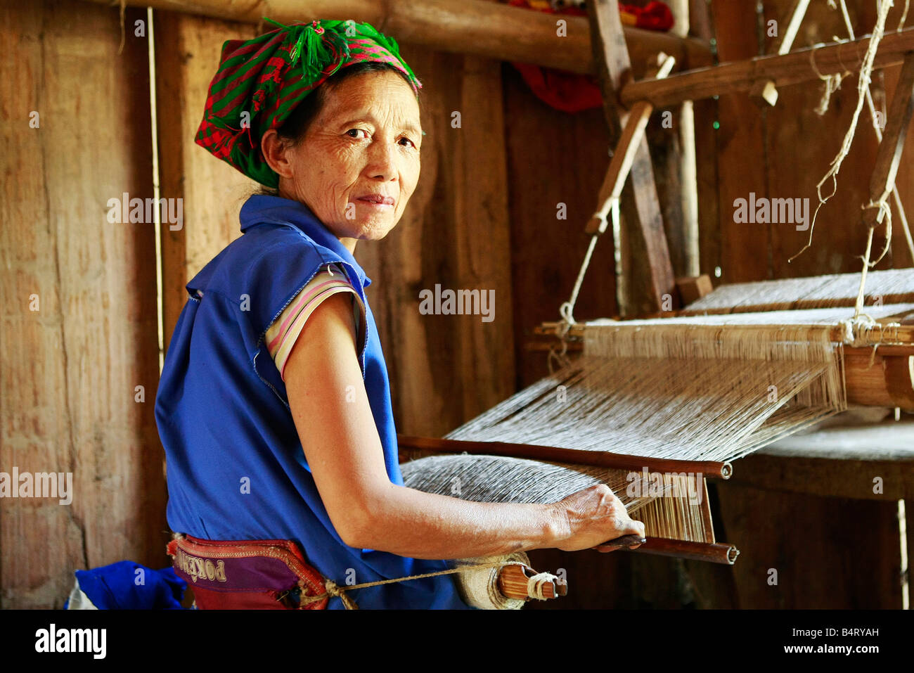 White Hmong tribeswoman weaving flax at a village in Ha Giang Province ...