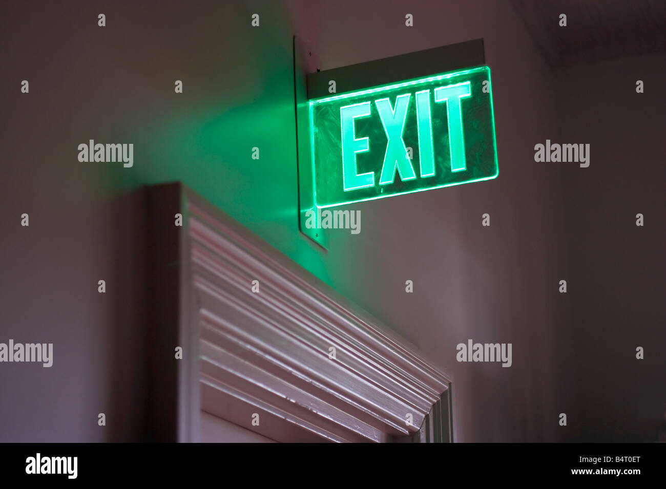 A glowing green sign indicates a building emergency exit Stock Photo ...