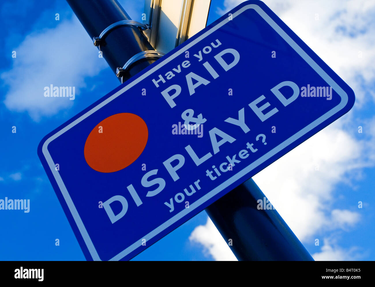 Pay and Display sign attached to a post in a car park with blue sky ...