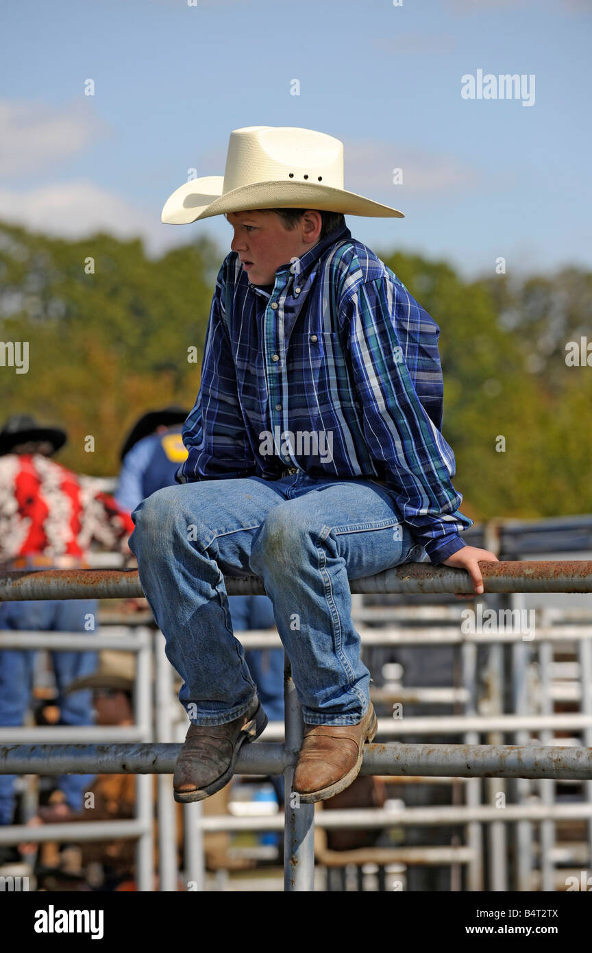 Teen cowboy sitting on fence Stock Photo - Alamy