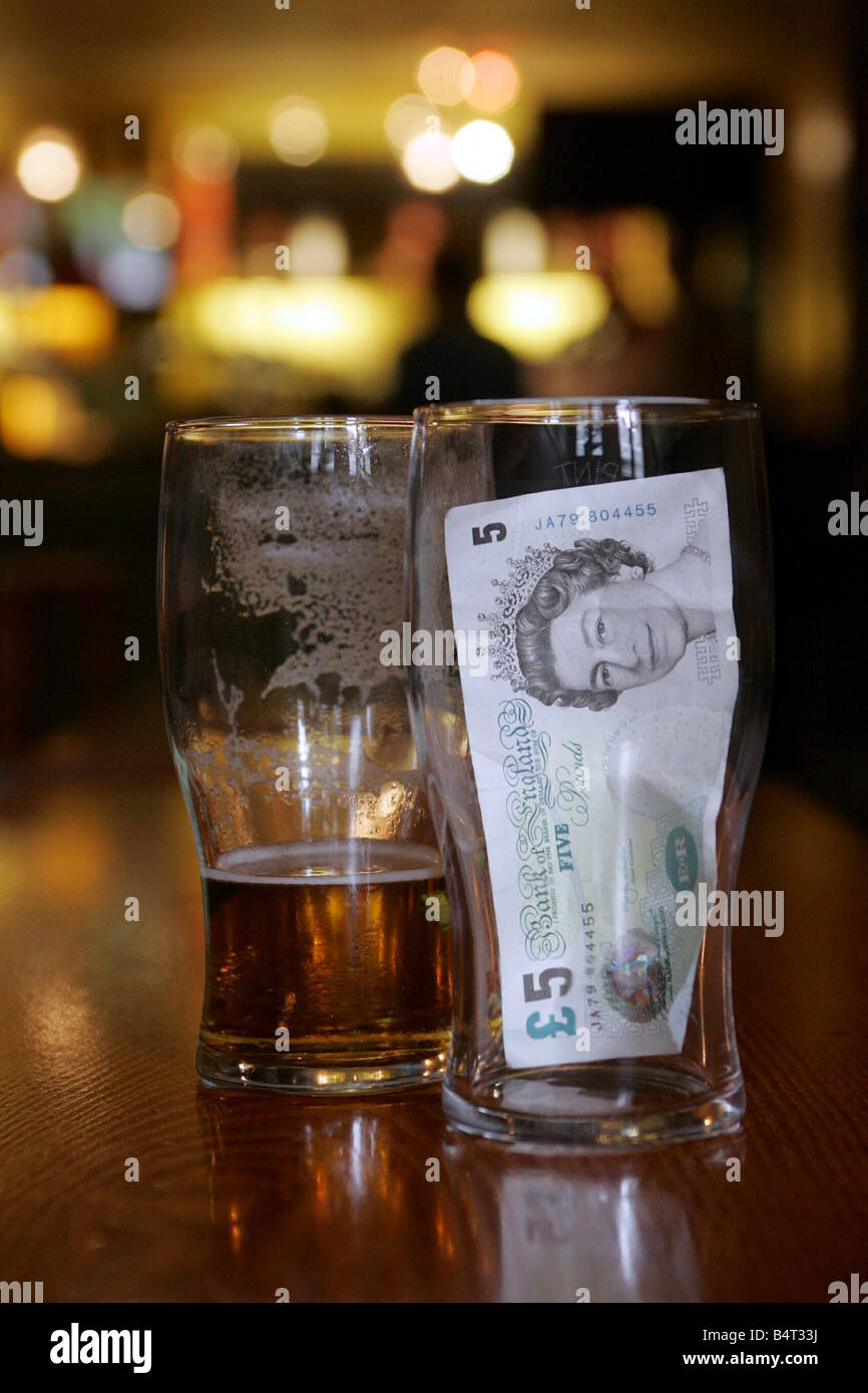 A a half drunk pint of beer with a 5 pound note Stock Photo - Alamy