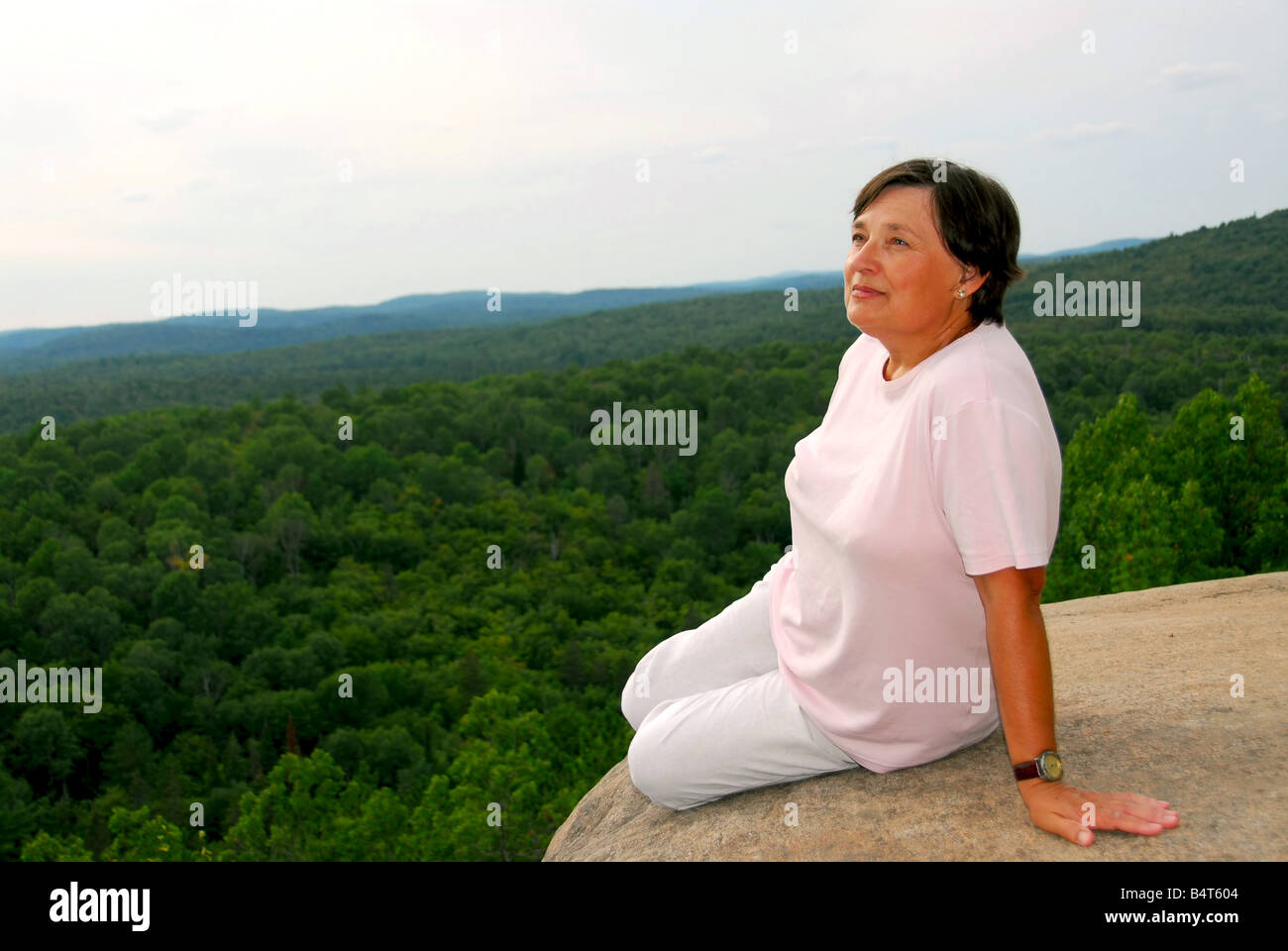 Mature woman sitting on cliff edge enjoying scenery Stock Photo - Alamy
