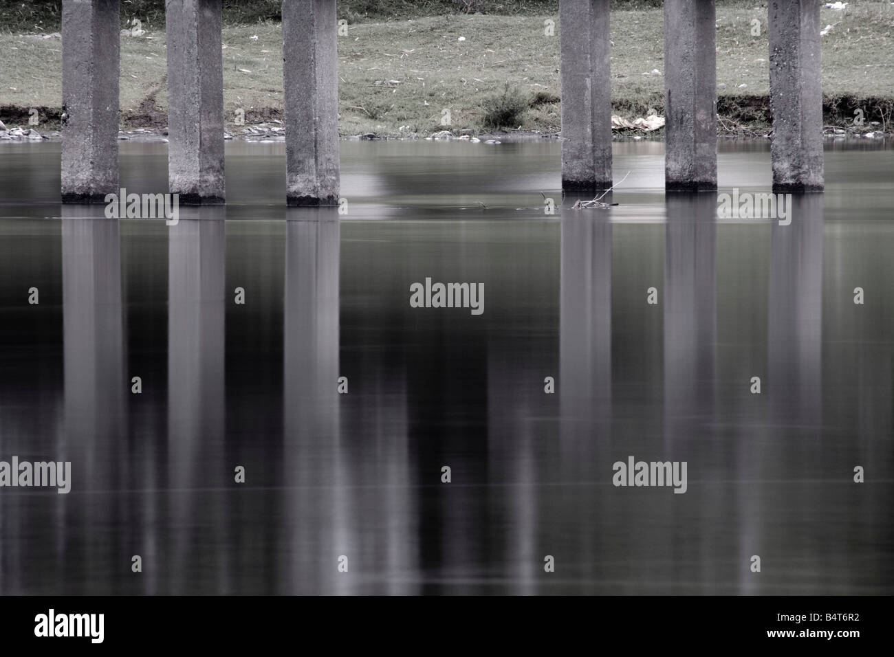 Pillars of destroyed bridge reflect on water Stock Photo - Alamy