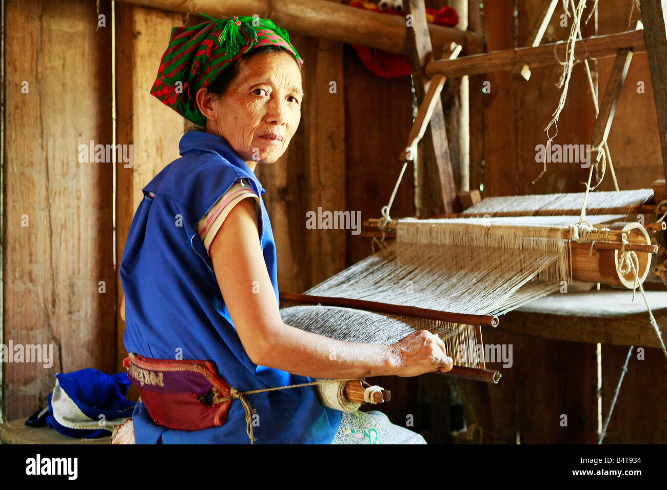 White Hmong tribeswoman weaving flax at a village in Ha Giang Province ...