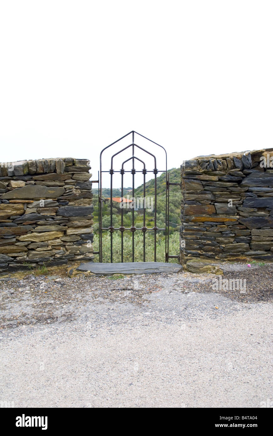 an unusual triangular wrought iron gate remains closed in a dry-stone ...