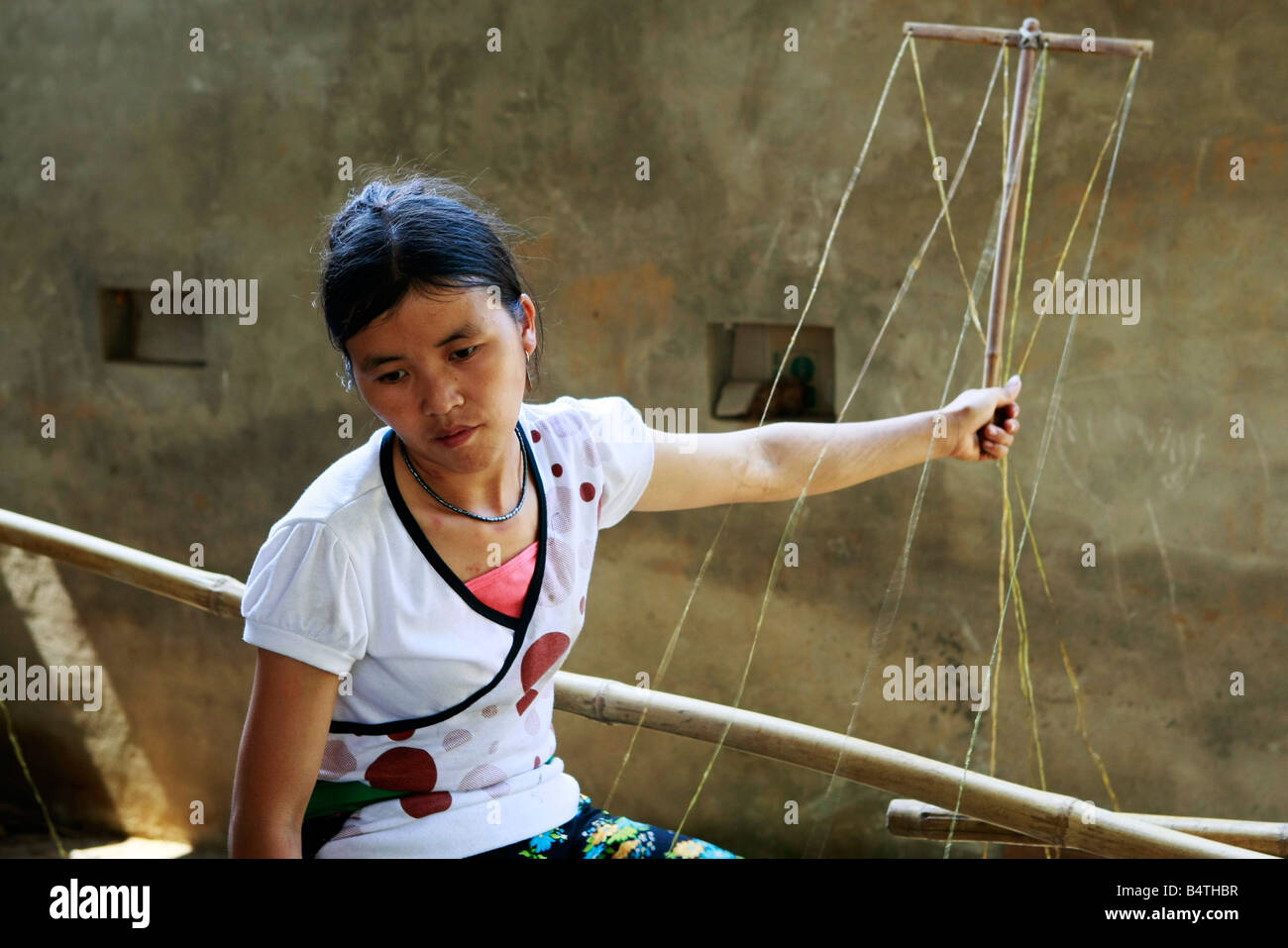 White Hmong tribeswoman weaving flax at a village in Ha Giang Province ...
