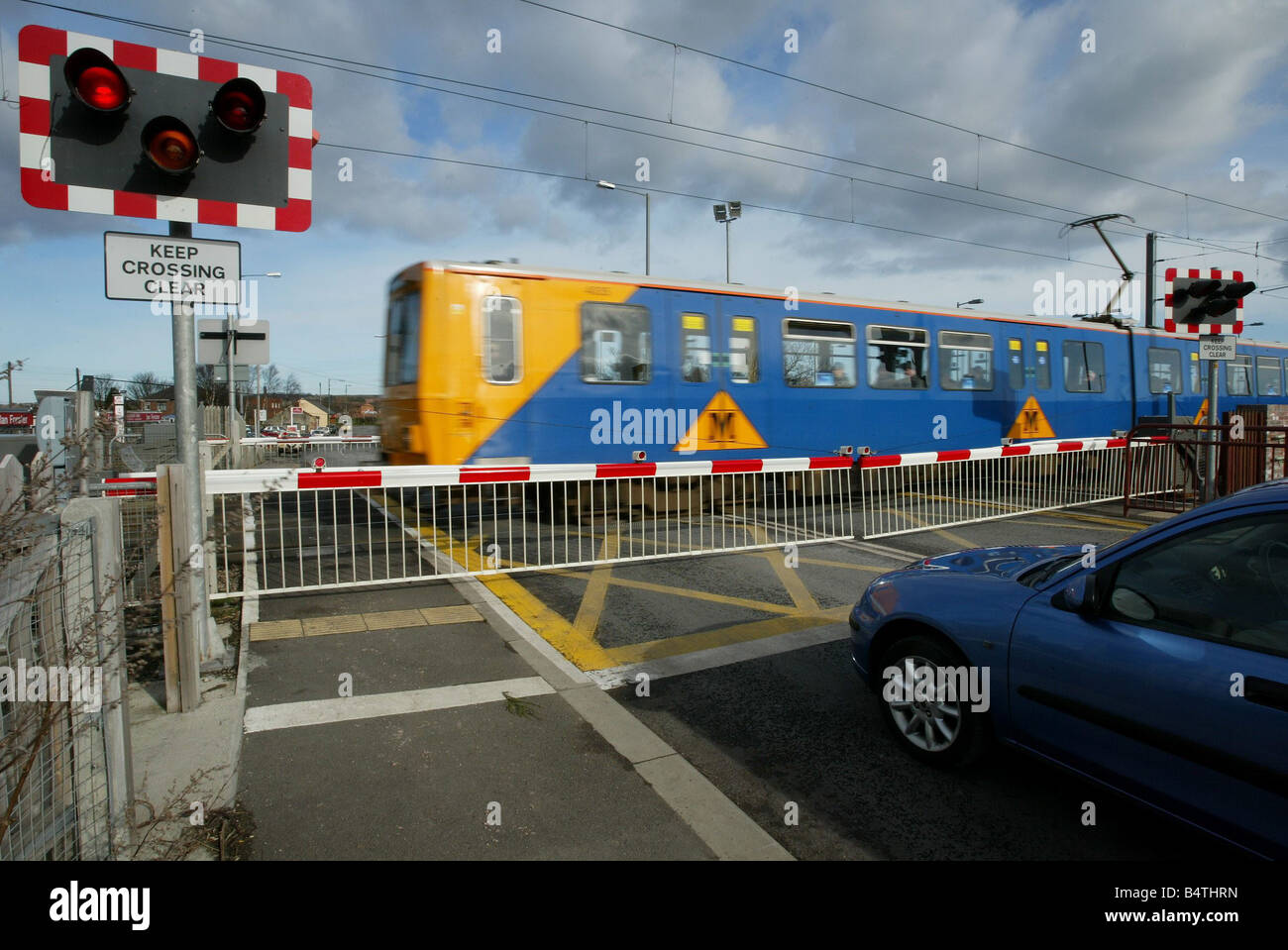 A car waits at a level crossing Train Railway Metro crossing at East ...