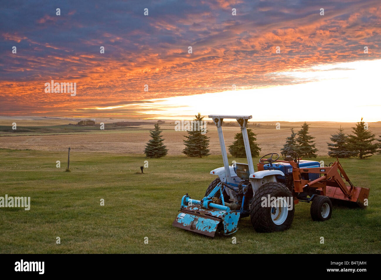 A small farm tractor against an autumn sunset Stock Photo - Alamy