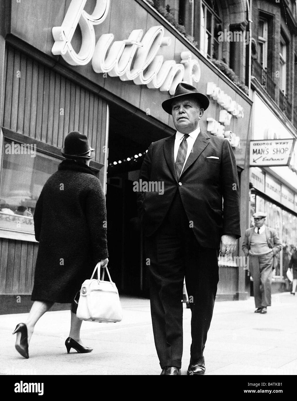 Billy Butlin walking past one of his Butlins shop on the high street ...