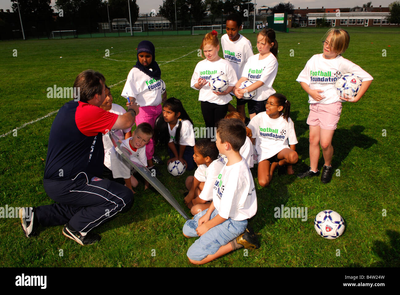 FA coach instructing primary school children i soccer skills and ...