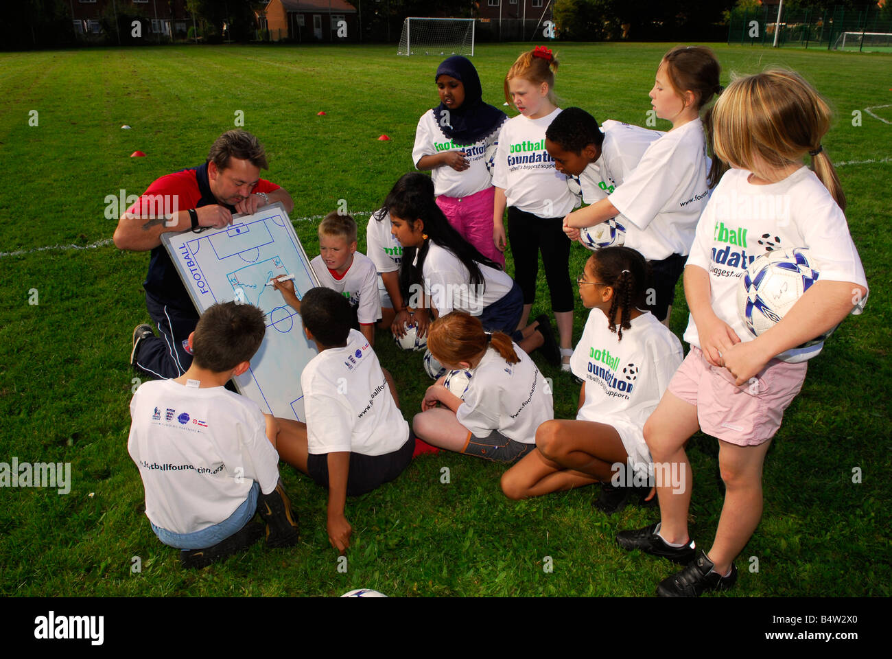 FA coach instructing primary school children in soccer skills and ...