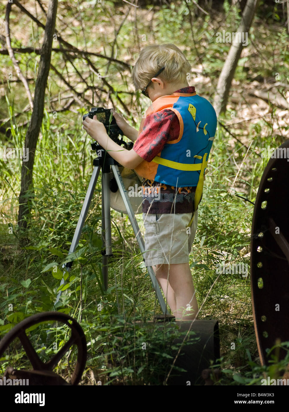 A young boy nature photographer checking out the view finder with a ...