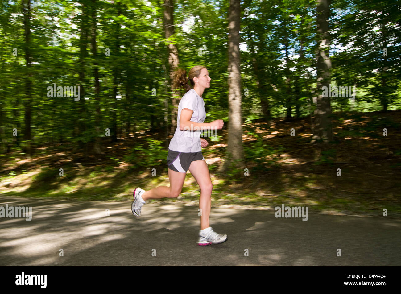 a woman runs down a park road Stock Photo - Alamy
