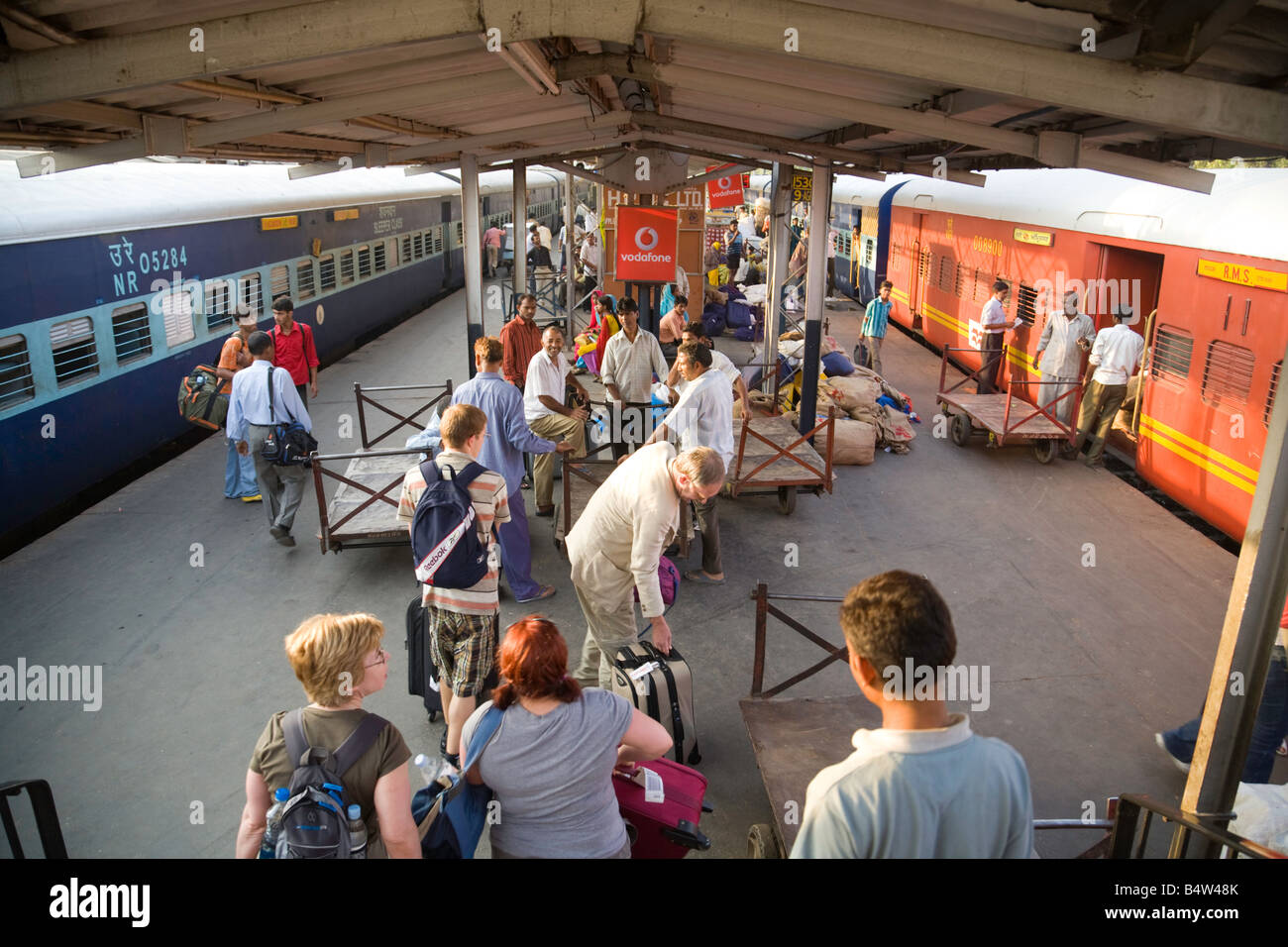 A crowded station platform with two trains at New Delhi train station ...
