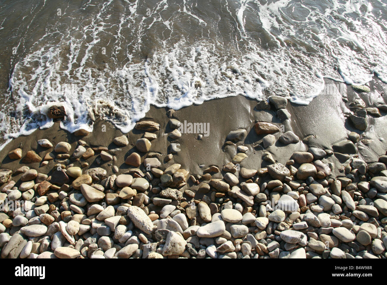 waves breaking onto rocks on sandy sea shore coast Stock Photo - Alamy