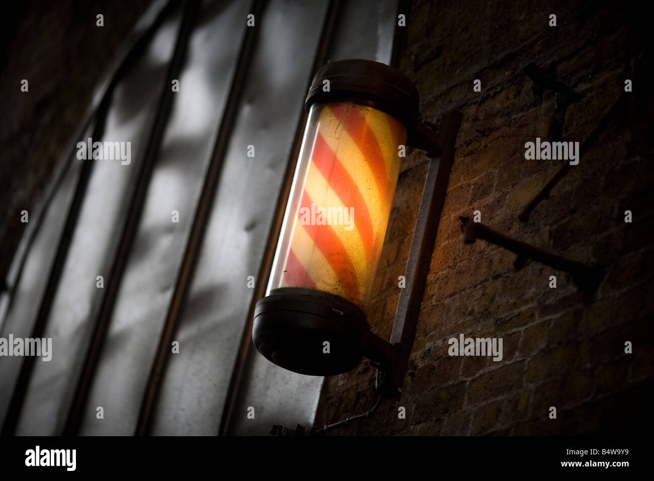 A traditional red and white barbers pole sign outside a barbershop in ...