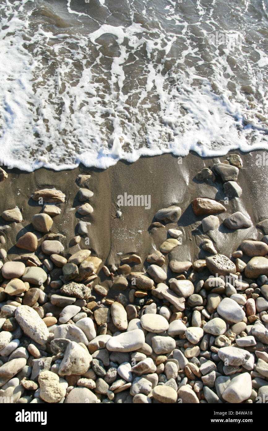 waves breaking onto rocks on sandy sea shore coast Stock Photo - Alamy