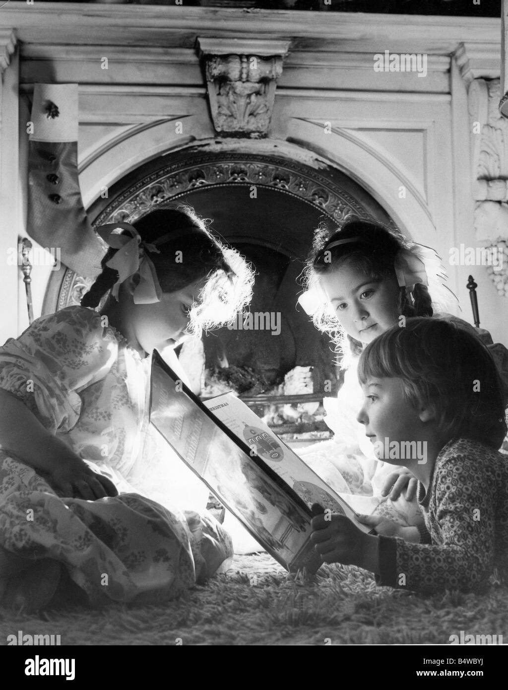 Three children listen to a fairytale in front of roaring fire at ...